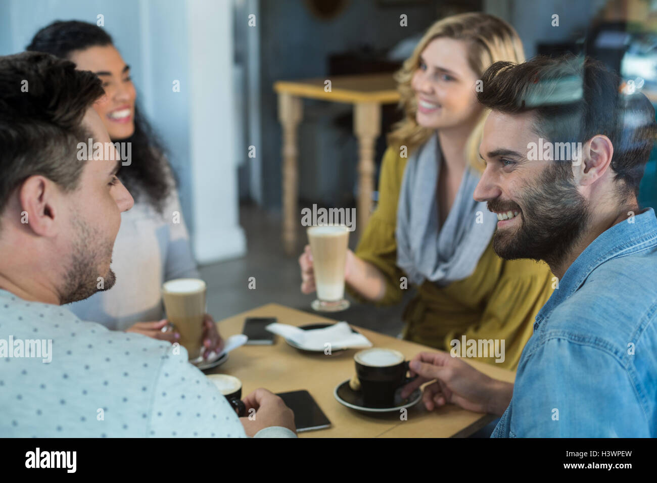 Smiling friends having a cup of coffee and cold coffee in caf├⌐ Stock ...