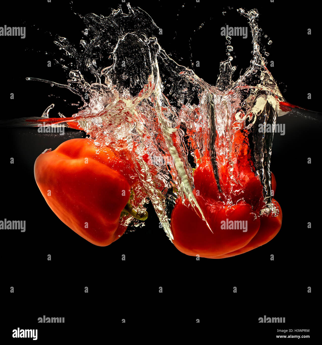 Group of bell pepper falling in water on black Stock Photo - Alamy