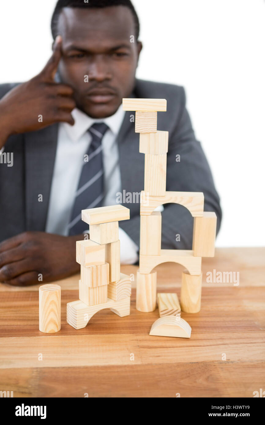 Thoughtful businessman building tower of wooden blocks Stock Photo - Alamy