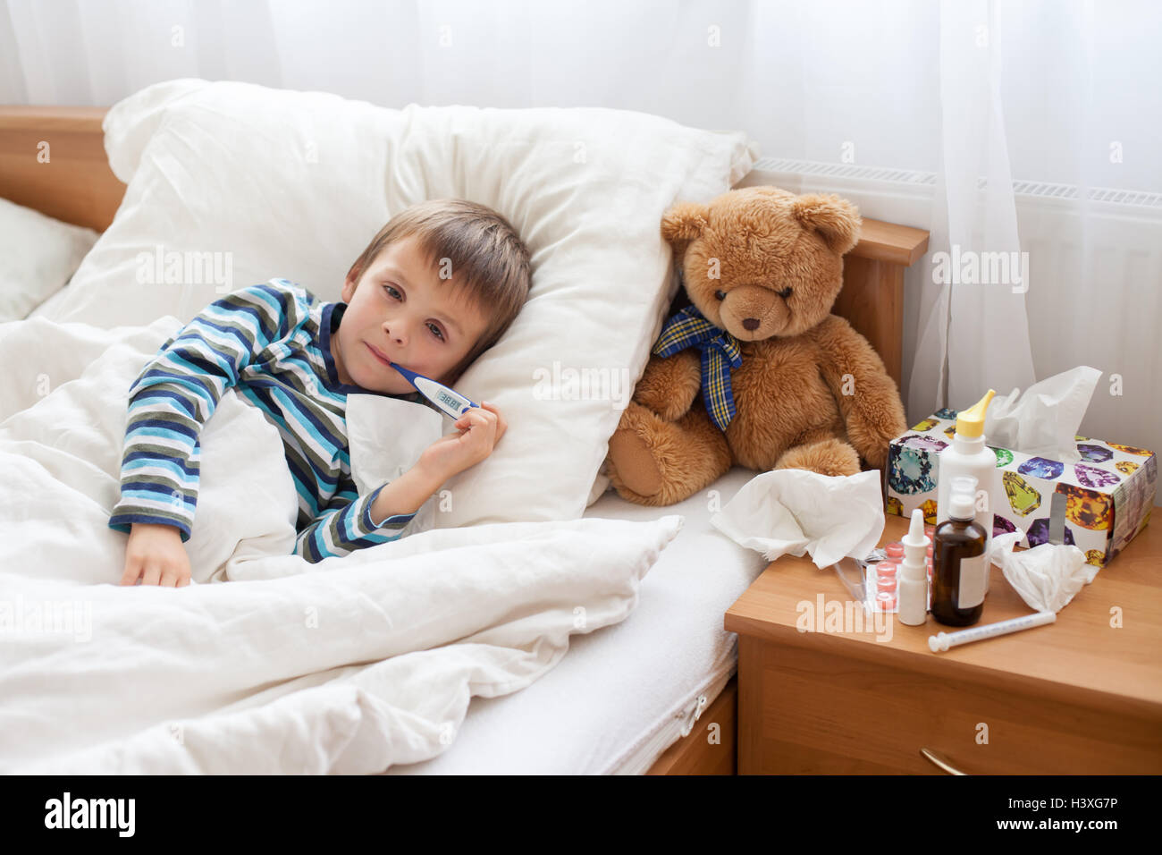 Sick child boy lying in bed with a fever, resting at home Stock Photo ...