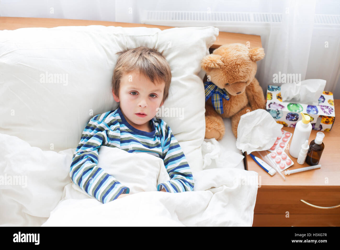 Sick child boy lying in bed with a fever, resting at home Stock Photo ...
