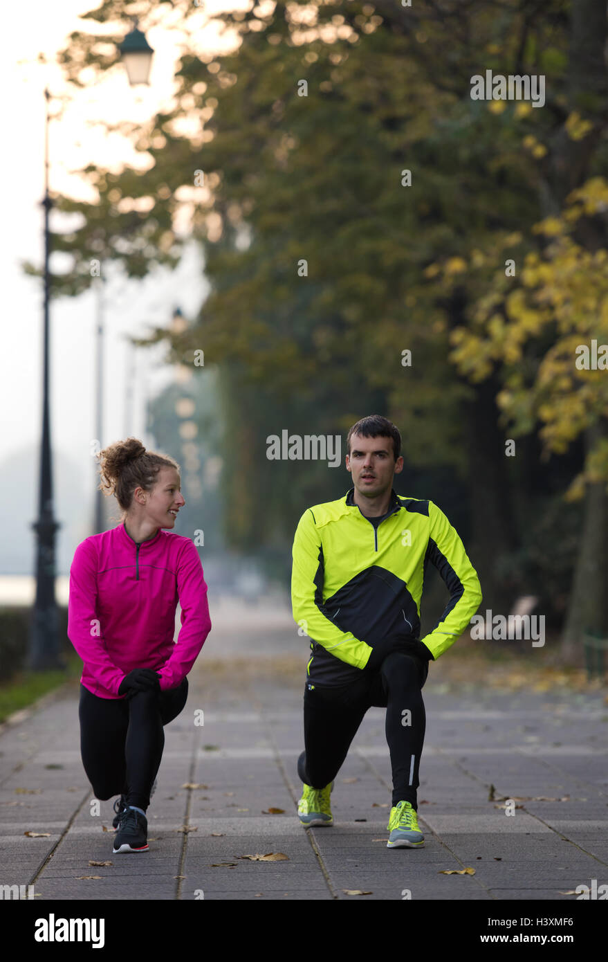 jogging couple warming up and stretching before morning running in the ...