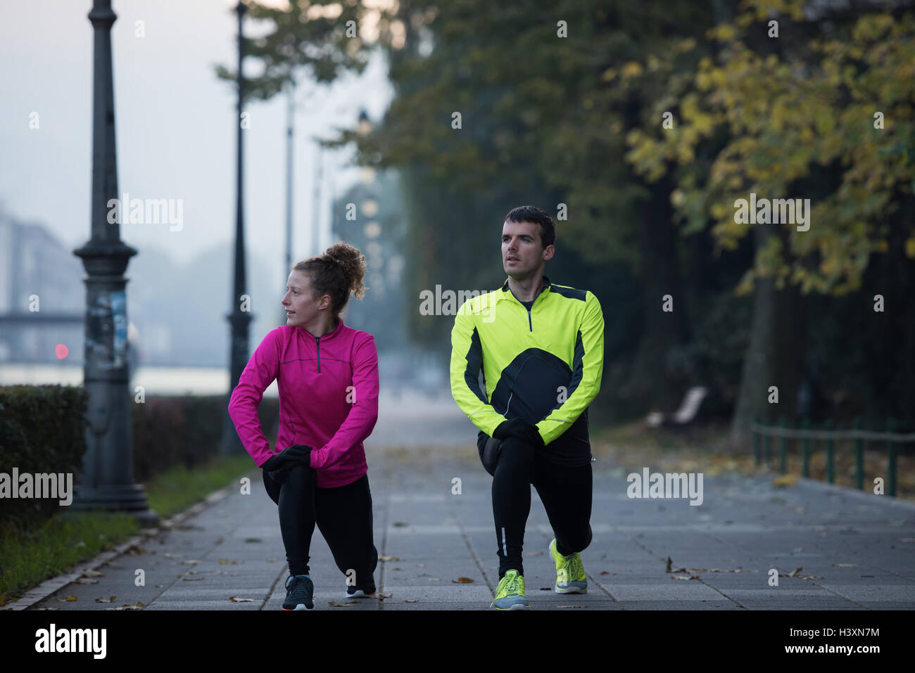 jogging couple warming up and stretching before morning running in the ...