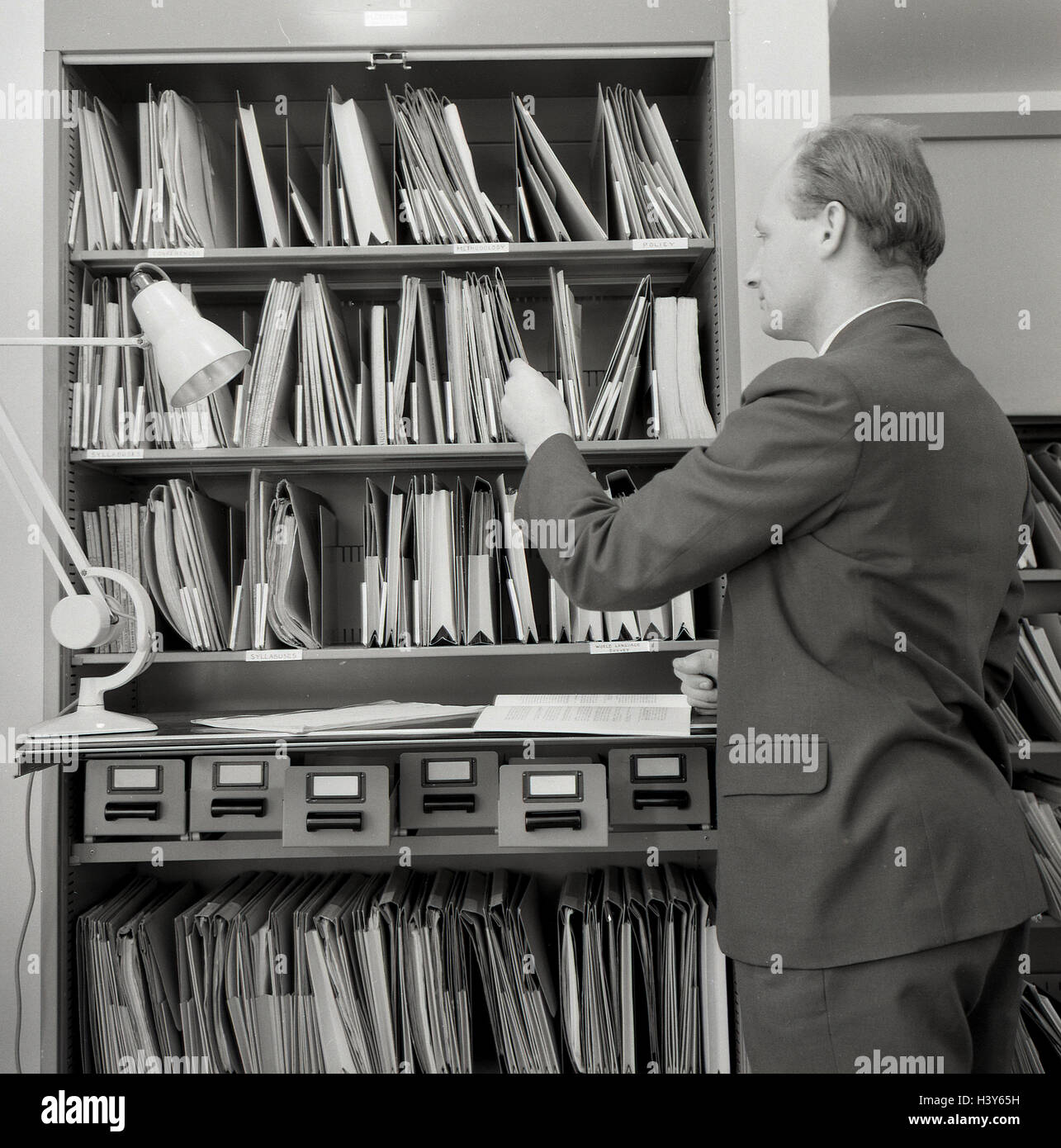 1960s, historical, male administrator looking through files or records ...