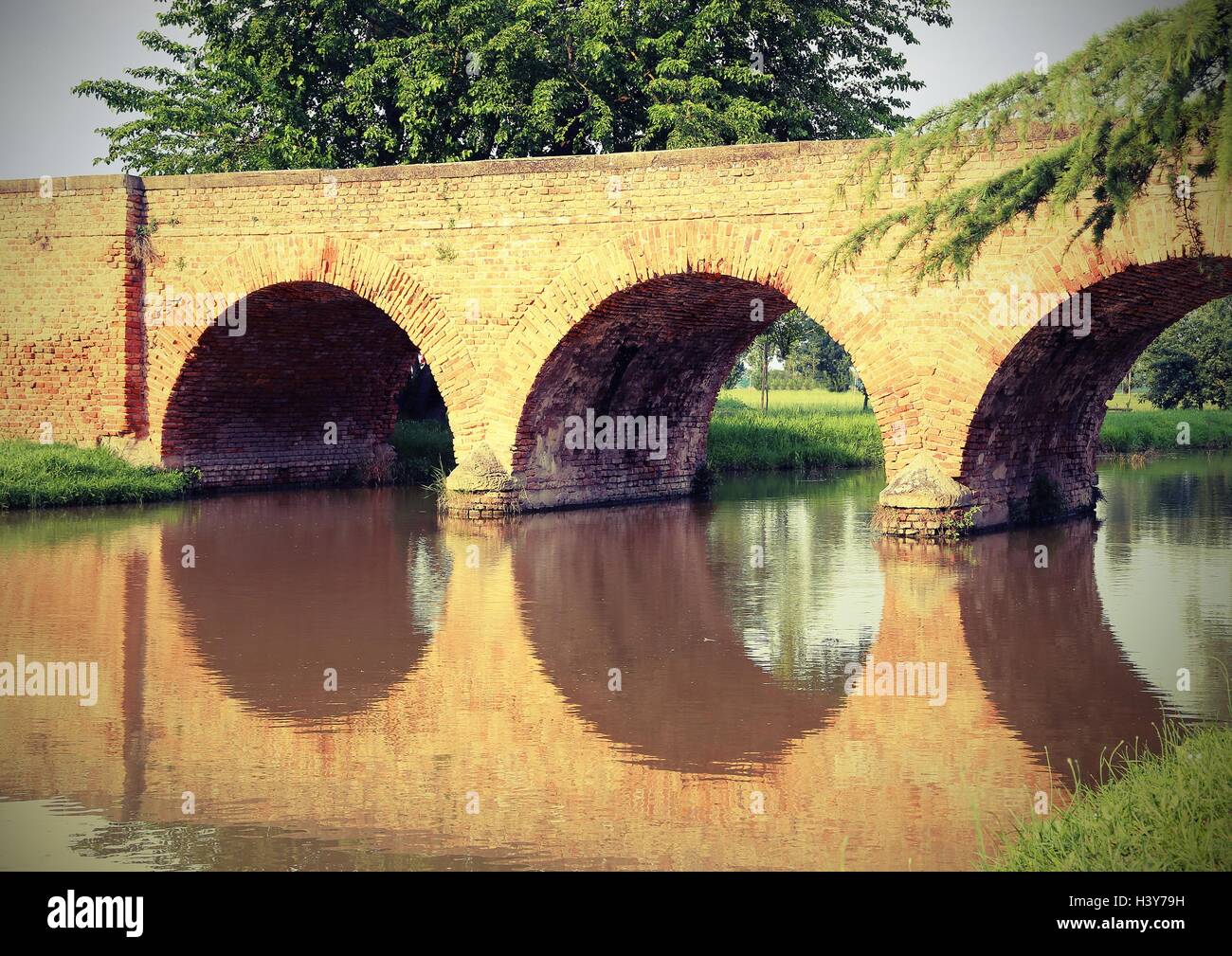 ancient arched bridge made with red bricks with the river Stock Photo ...