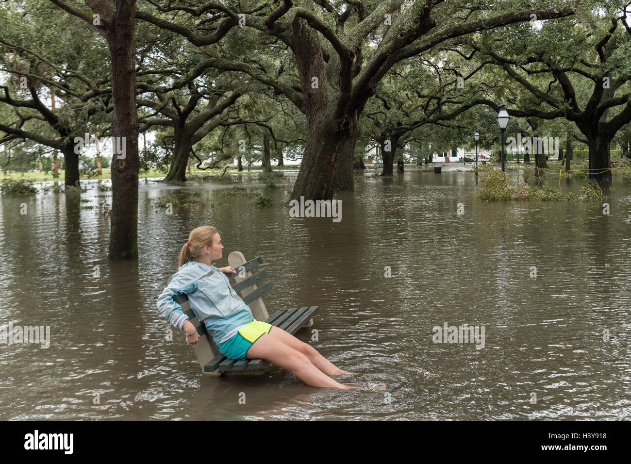A young girl sits on a park bench surrounded by flood water in White ...