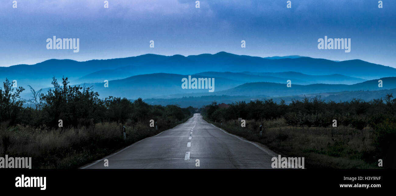 Panoramic view of an old road leading to the blue hills Stock Photo - Alamy