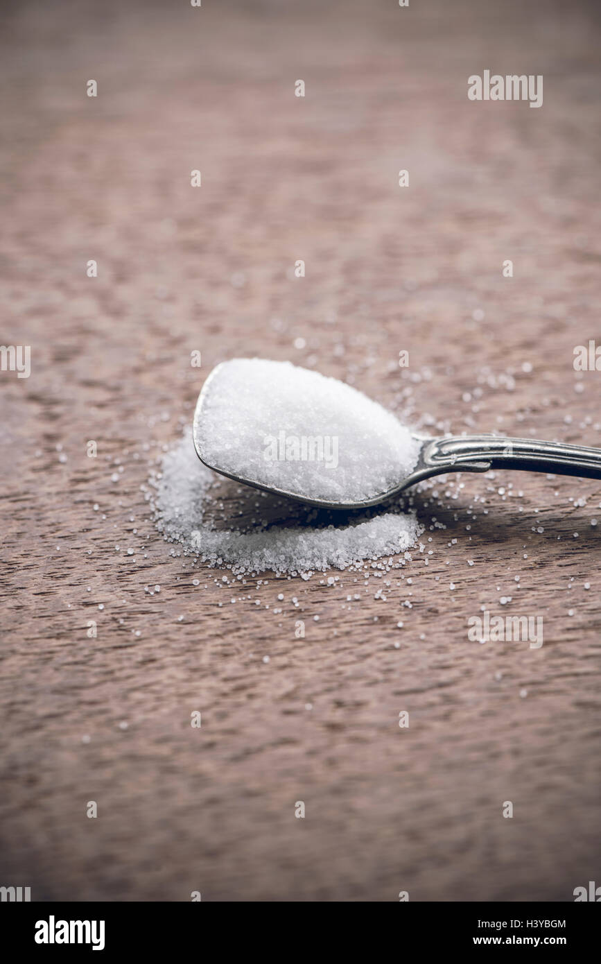 Salt on a spoon in close up. Wooden table as background with copy space ...