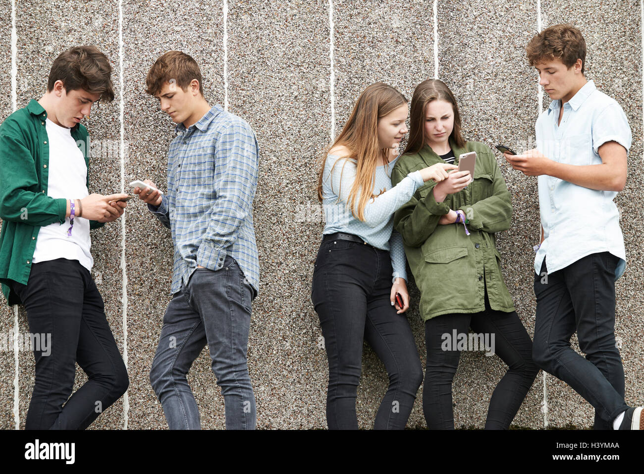 Group Of Teenagers Sharing Text Message On Mobile Phones Stock Photo ...