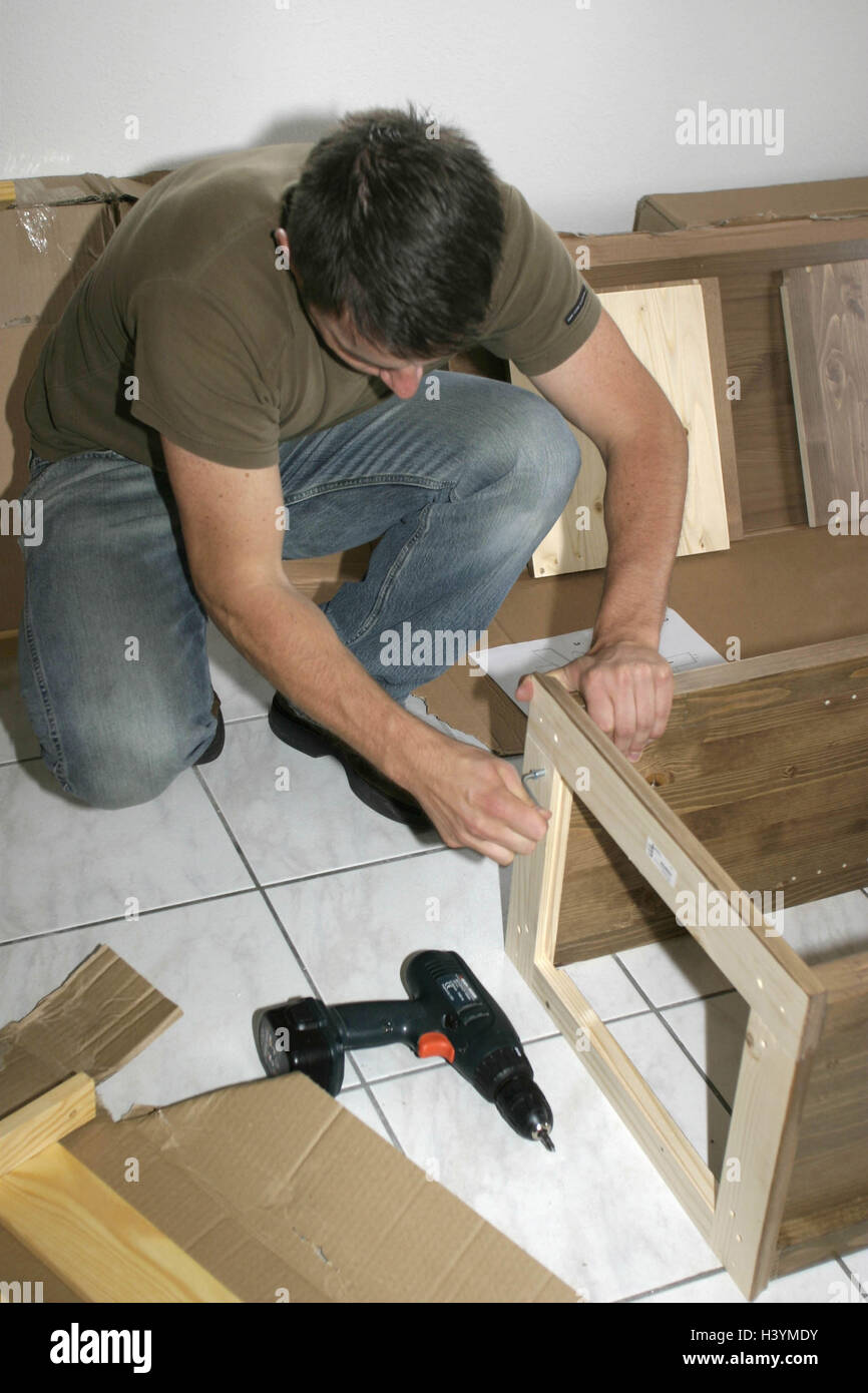 Man, young, cupboard assemble, cupboard cuts, battery power ...