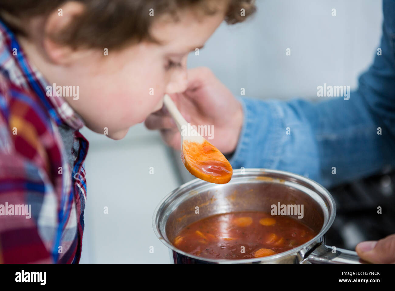 Son tasting food in the kitchen Stock Photo - Alamy