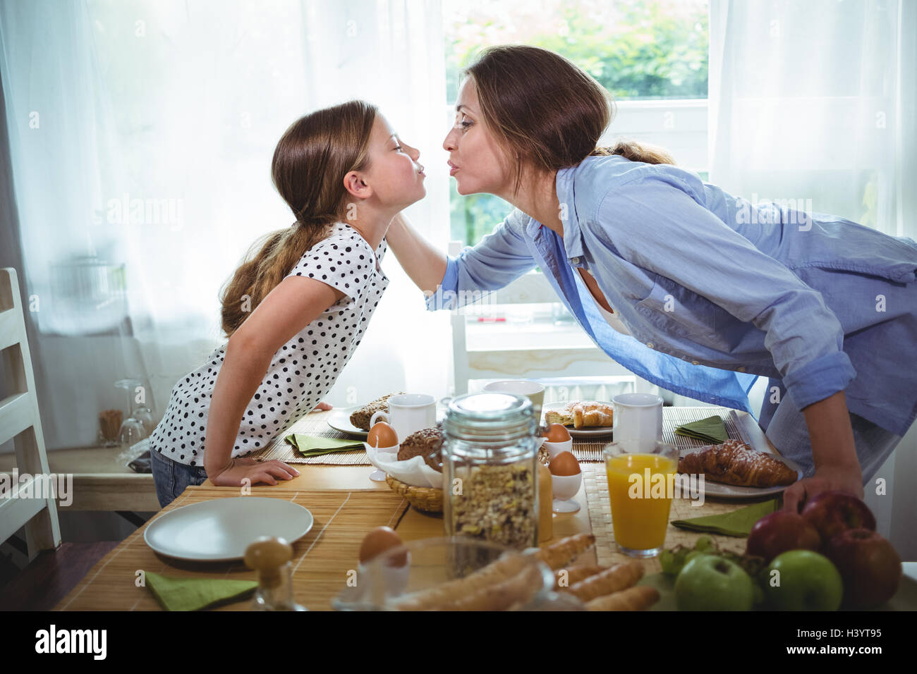 Mother and daughter kissing each other while having breakfast Stock ...