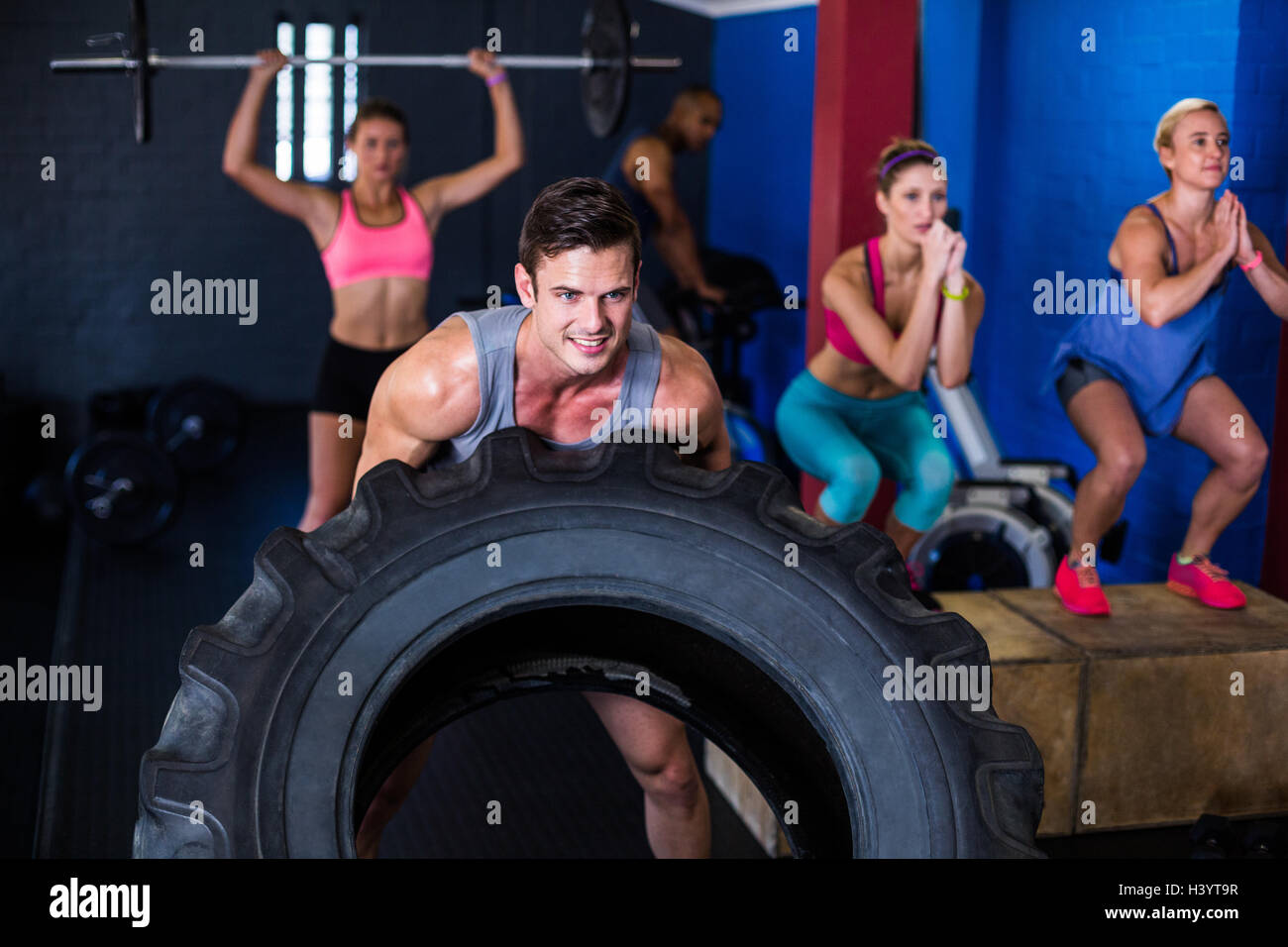 Smiling man lifting tire in gym Stock Photo - Alamy
