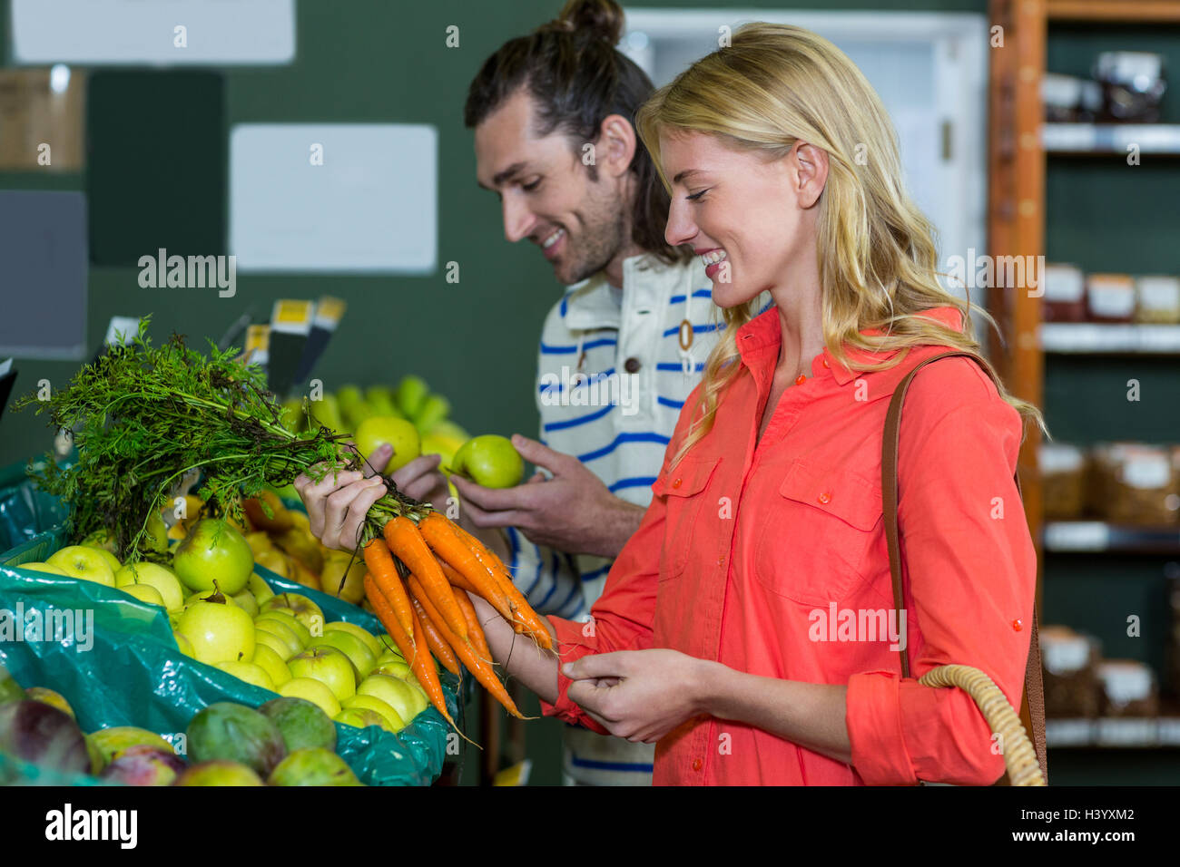 Happy couple selecting fruits and carrots in organic section Stock ...