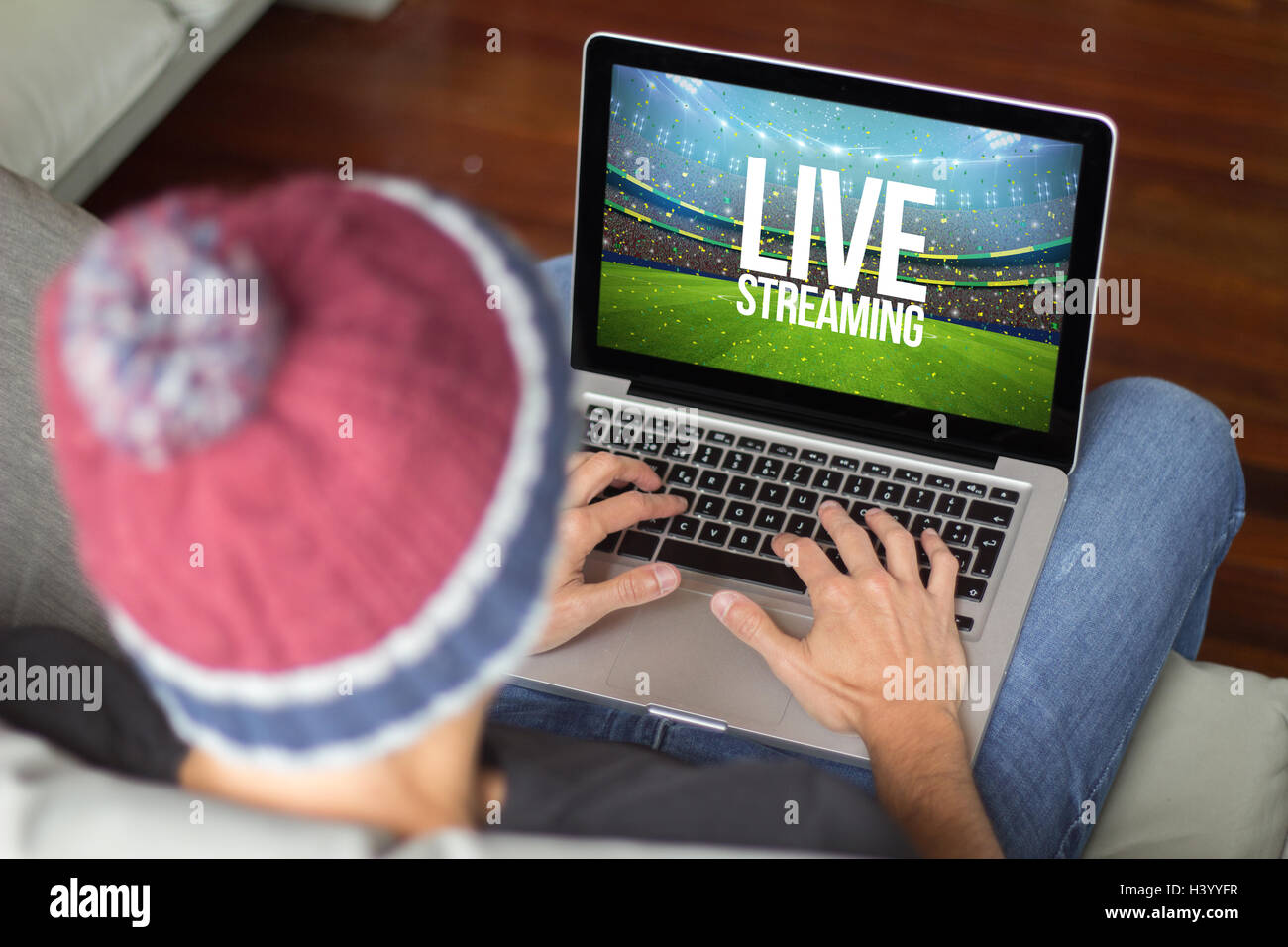 Young man watching live streaming sports event. All screen graphics are ...
