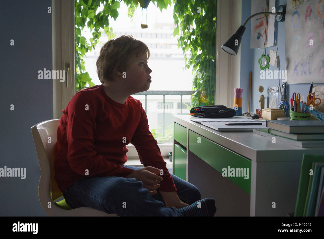 Boy reading alphabets while sitting at desk in room Stock Photo - Alamy