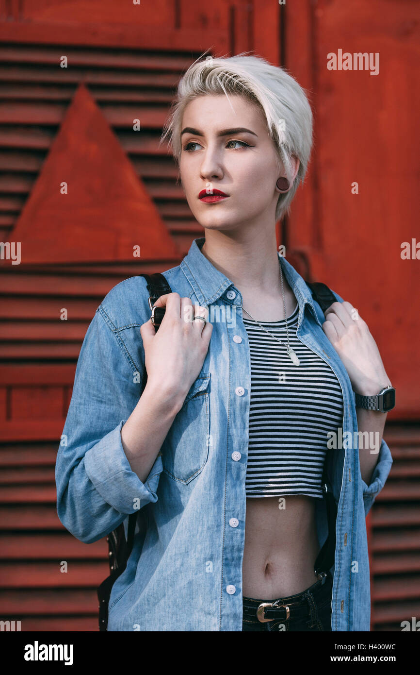 Confident young woman standing against red brick wall Stock Photo - Alamy