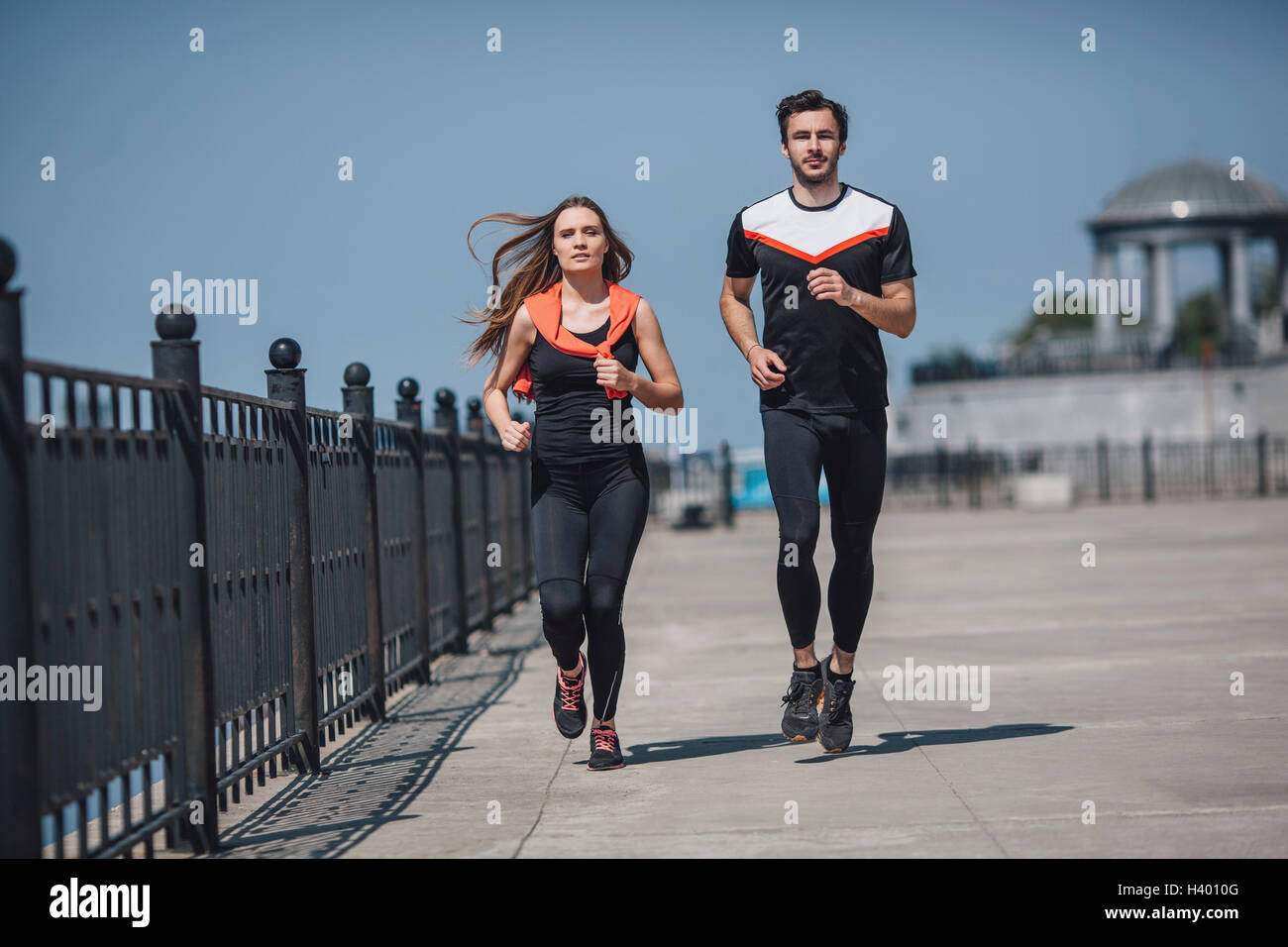 Full length of determined people running on promenade against clear sky ...