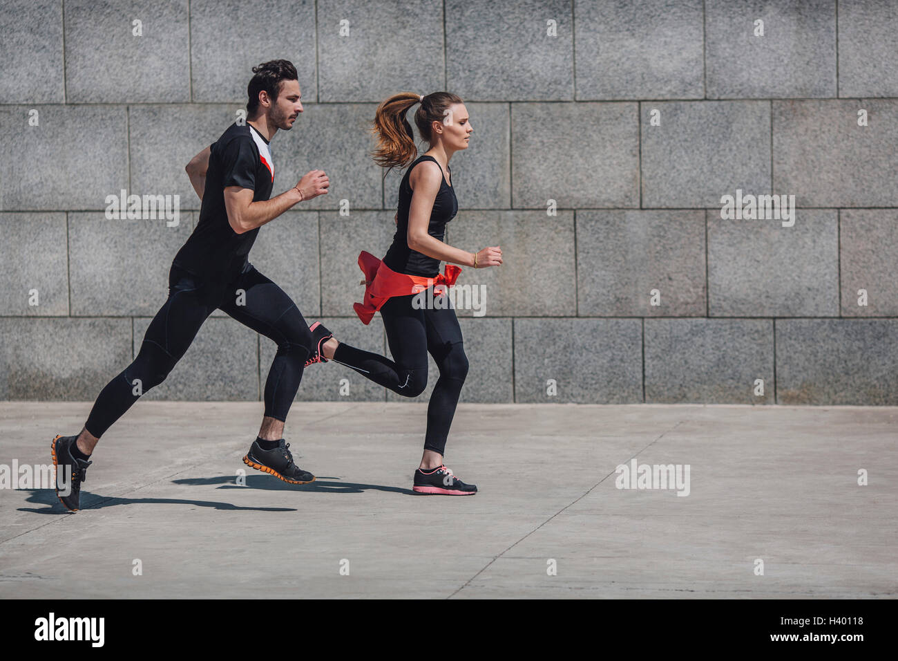 Side view of people jogging on sidewalk by wall Stock Photo - Alamy