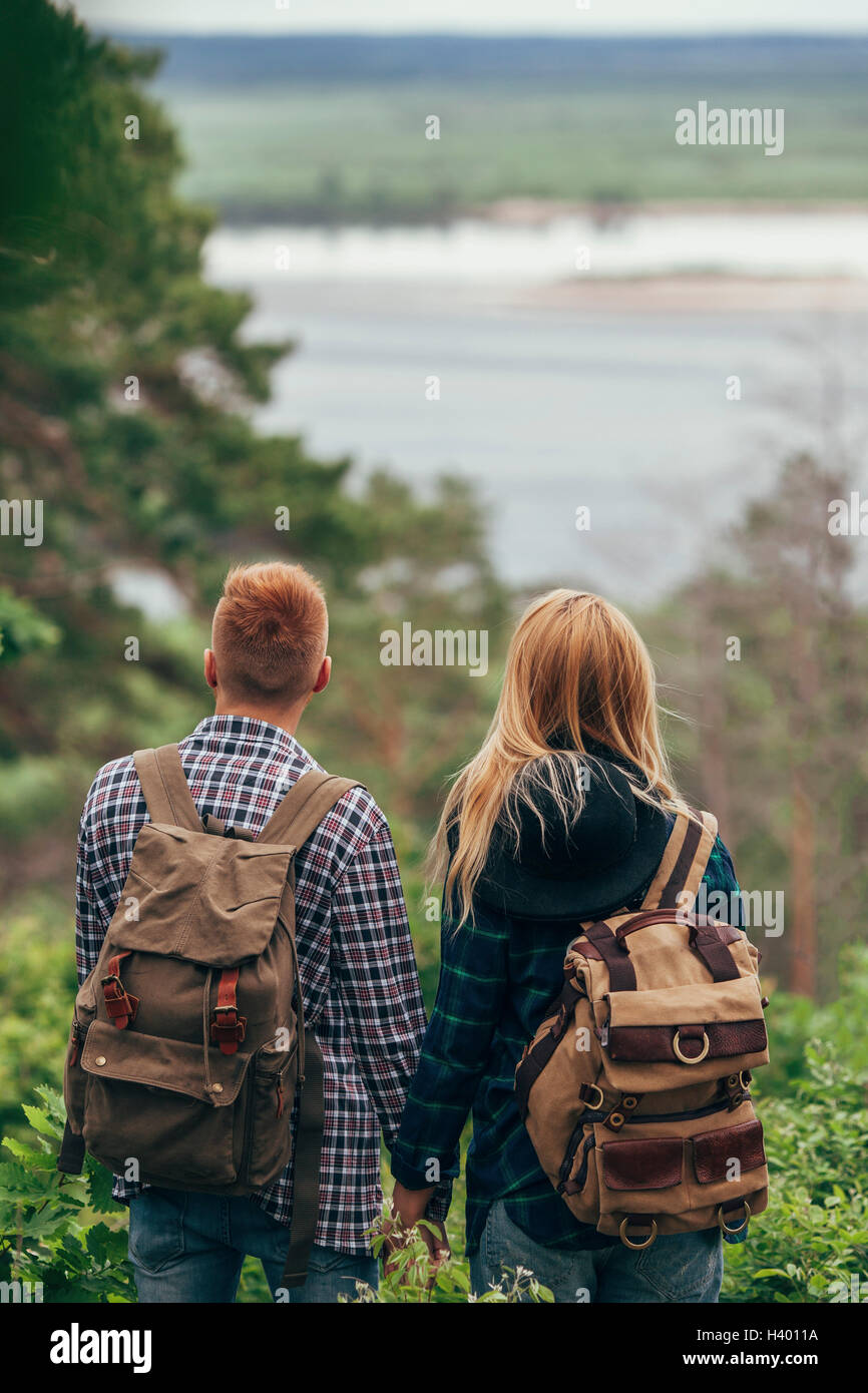 Rear view of couple wearing backpack standing in forest Stock Photo - Alamy