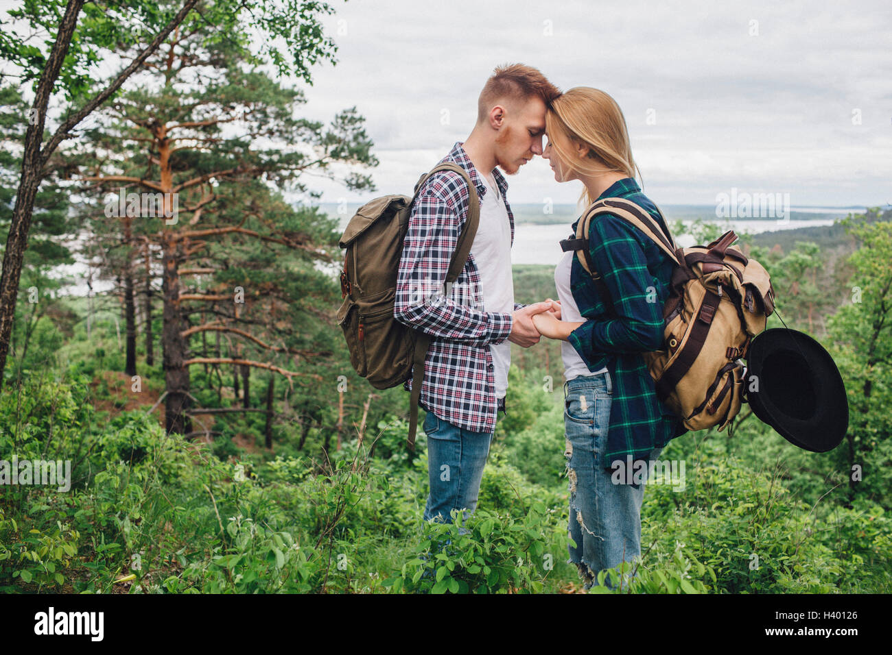 Loving couple holding hands while standing amidst plants at forest ...