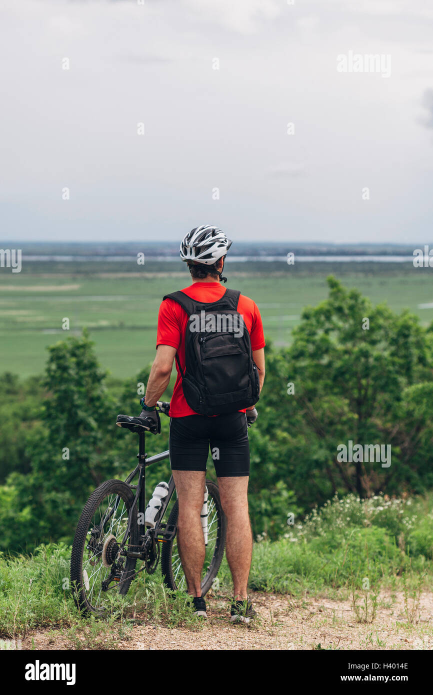 Rear view of man standing with mountain bike on hill Stock Photo - Alamy