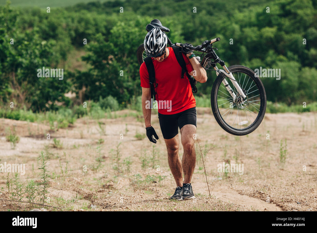 Determined man carrying mountain bike up hill Stock Photo - Alamy