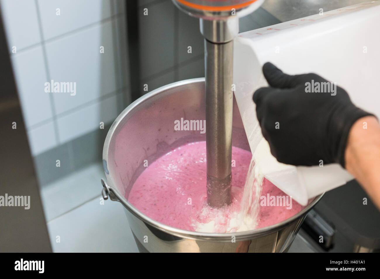 Detail of man mixing ingredient into strawberry ice cream in machine ...