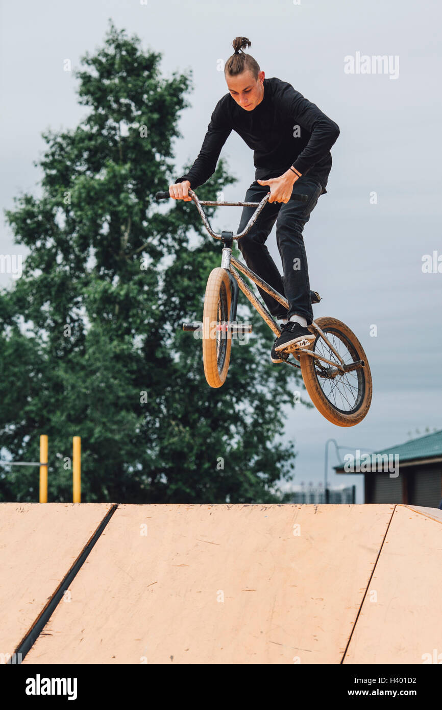 Low angle view of teenager performing stunt on ramp at skateboard park ...