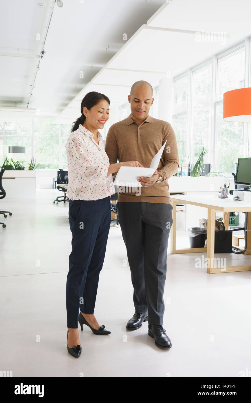 Businessman discussing with female colleague over file at creative ...