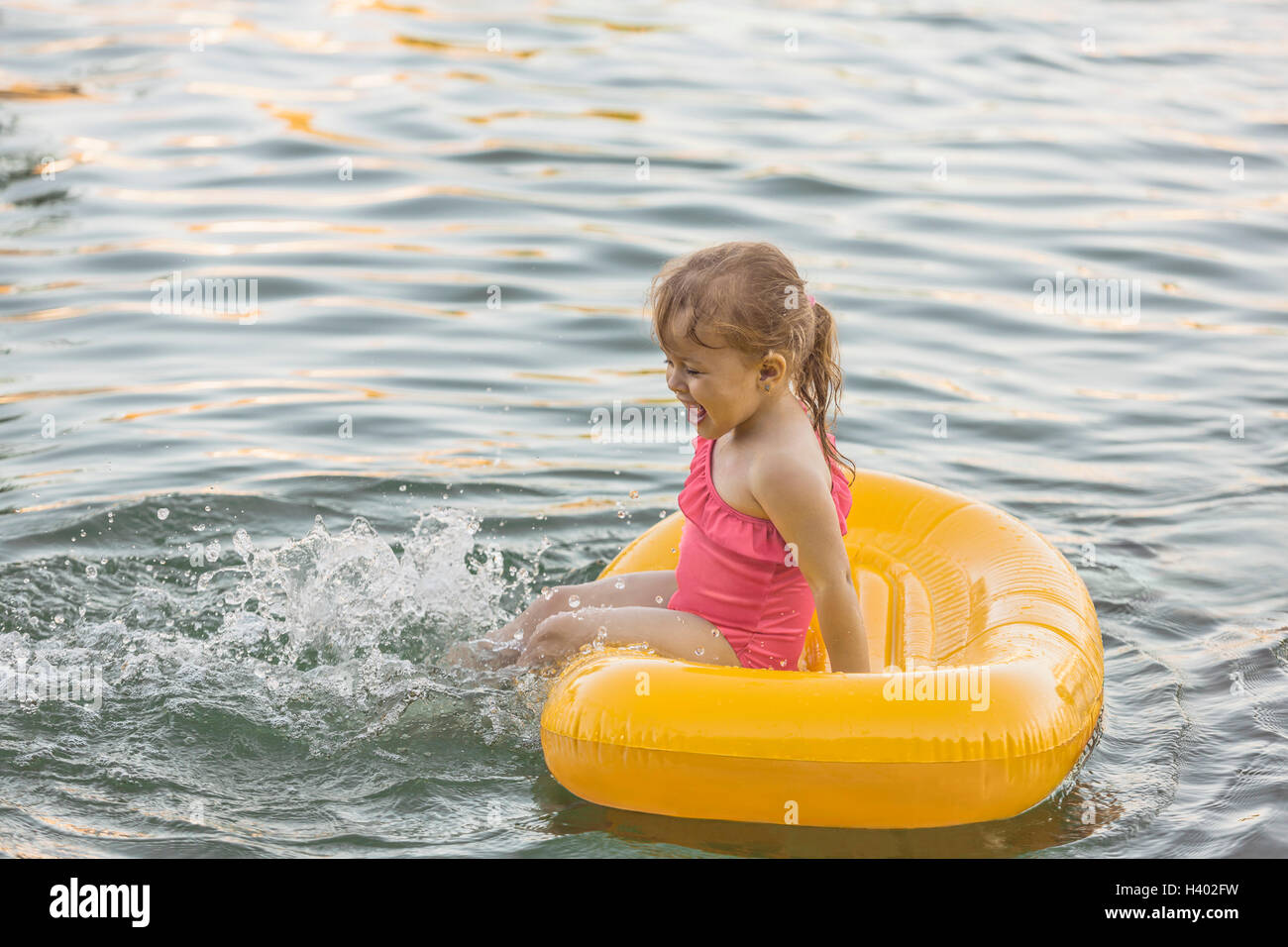 Cheerful girl sitting on raft and playing in lake Stock Photo - Alamy