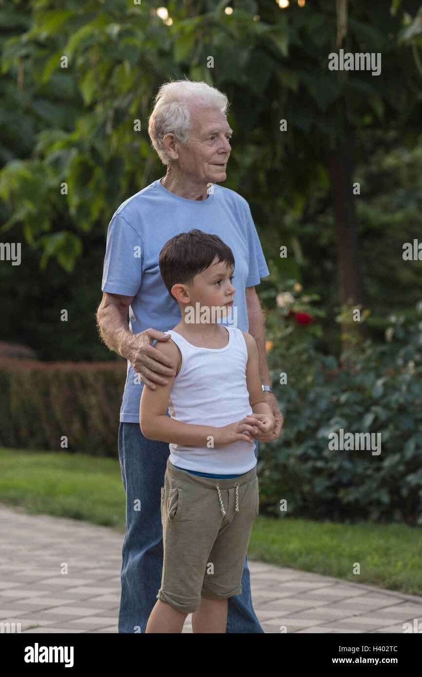 Smiling grandfather standing with grandson on footpath at park Stock ...