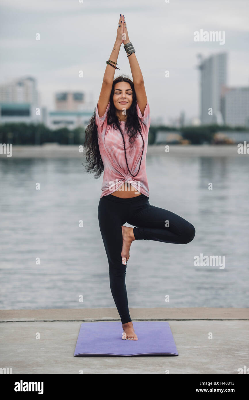 Beautiful woman practicing yoga in Tree Pose against river Stock Photo ...