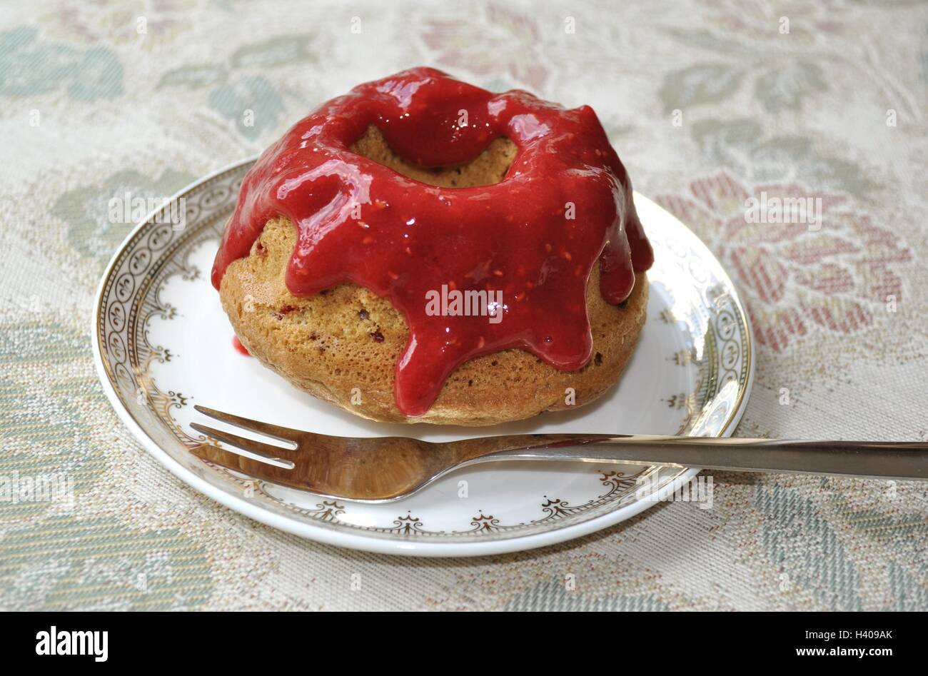 Mini sponge fruit cake with raspberry icing on white and gold porcelain ...