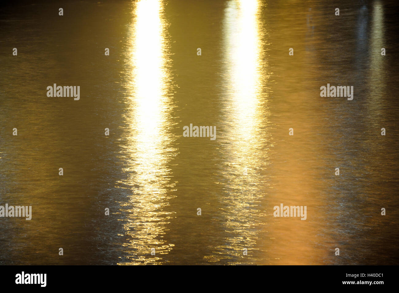 An abstract image of golden light reflecting off the surface of water ...