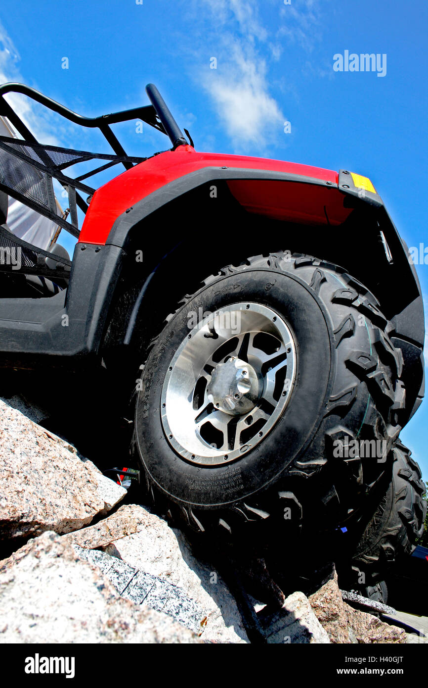 red four-wheel motorcycle standing on a pile of granite on a background ...