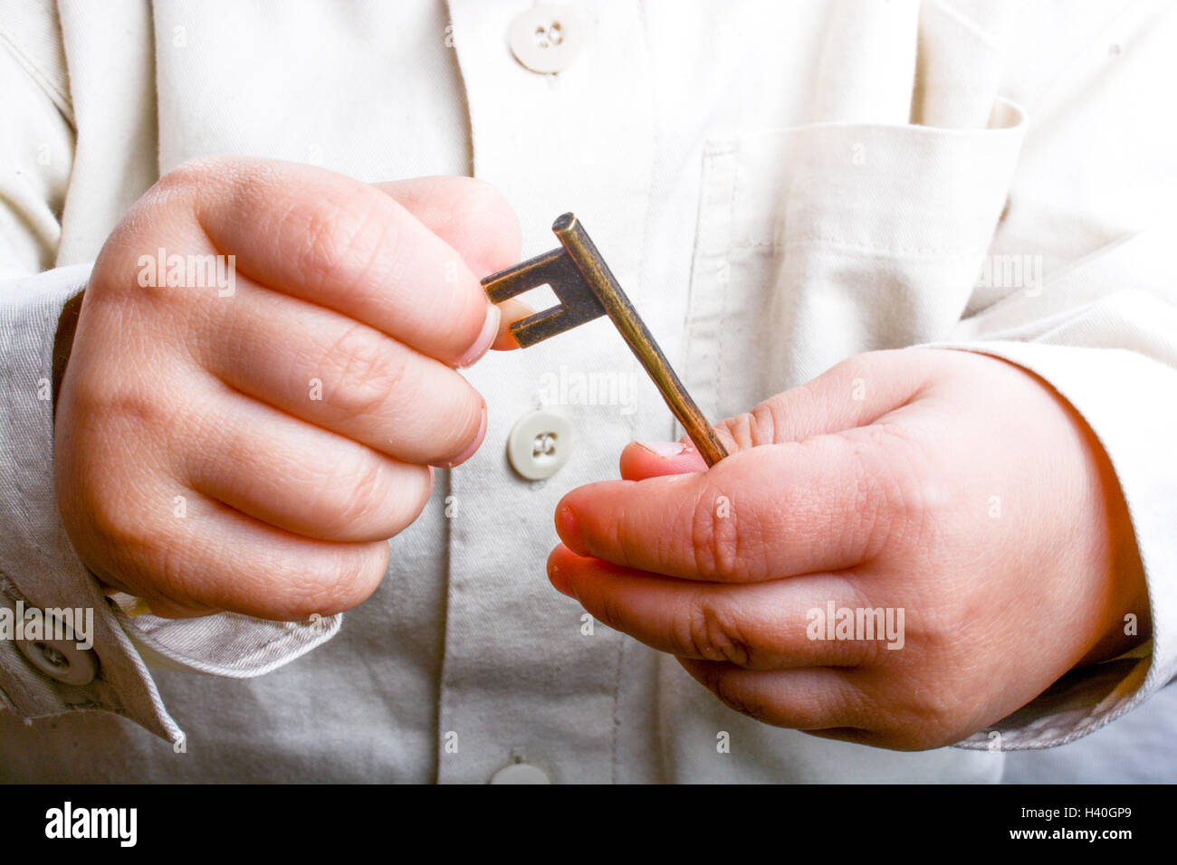 baby's hand holding a retro styled metal key on a white background ...