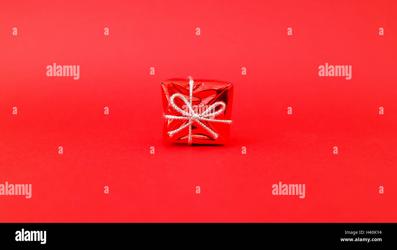 Red gift with a red background Stock Photo - Alamy