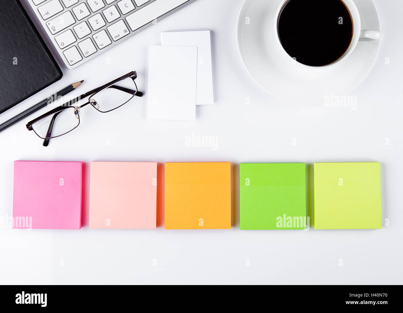 White keyboard with glasses and sticky note papers on white background ...