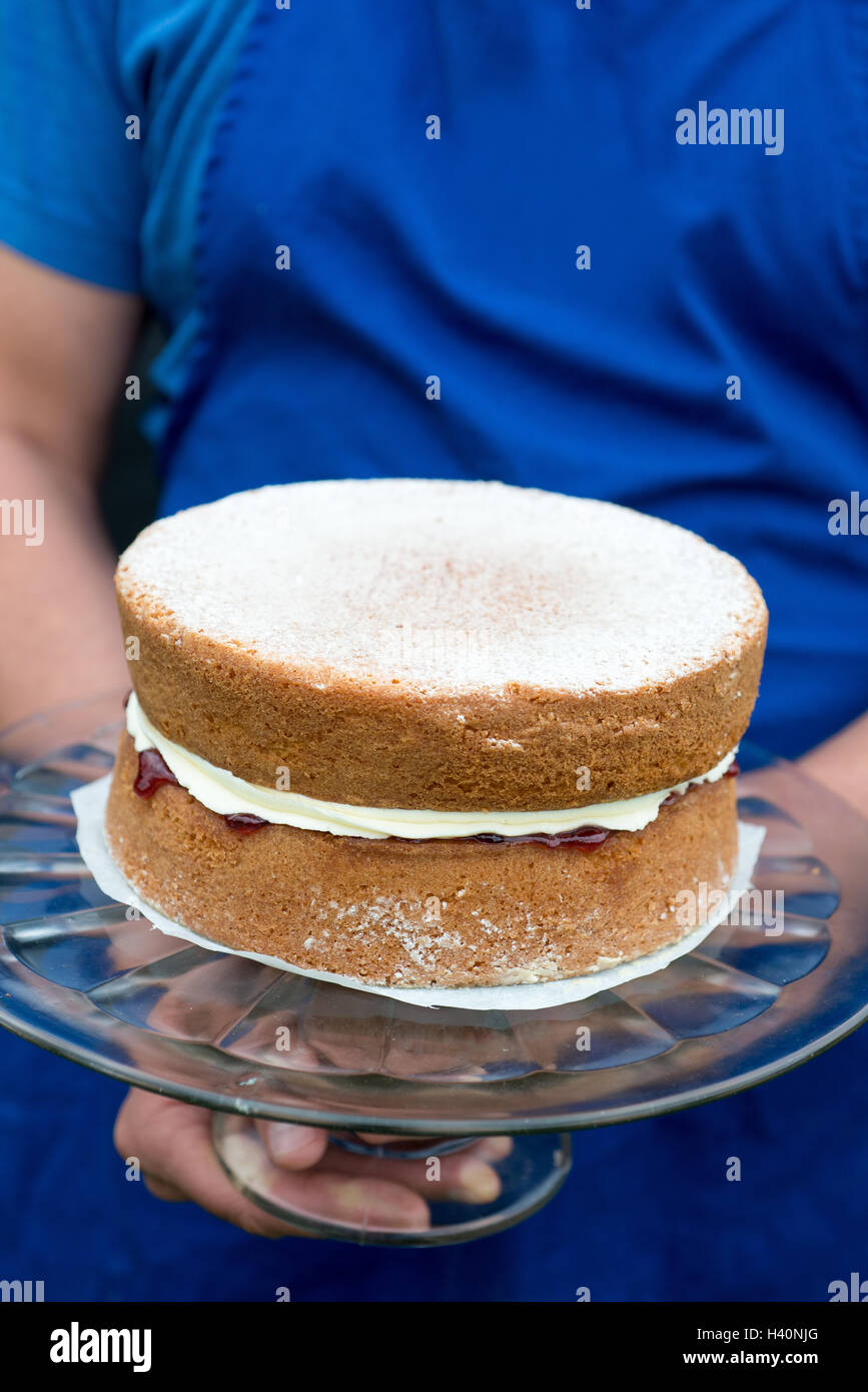 a glass cake stand held by person with traditional homemade victoria ...