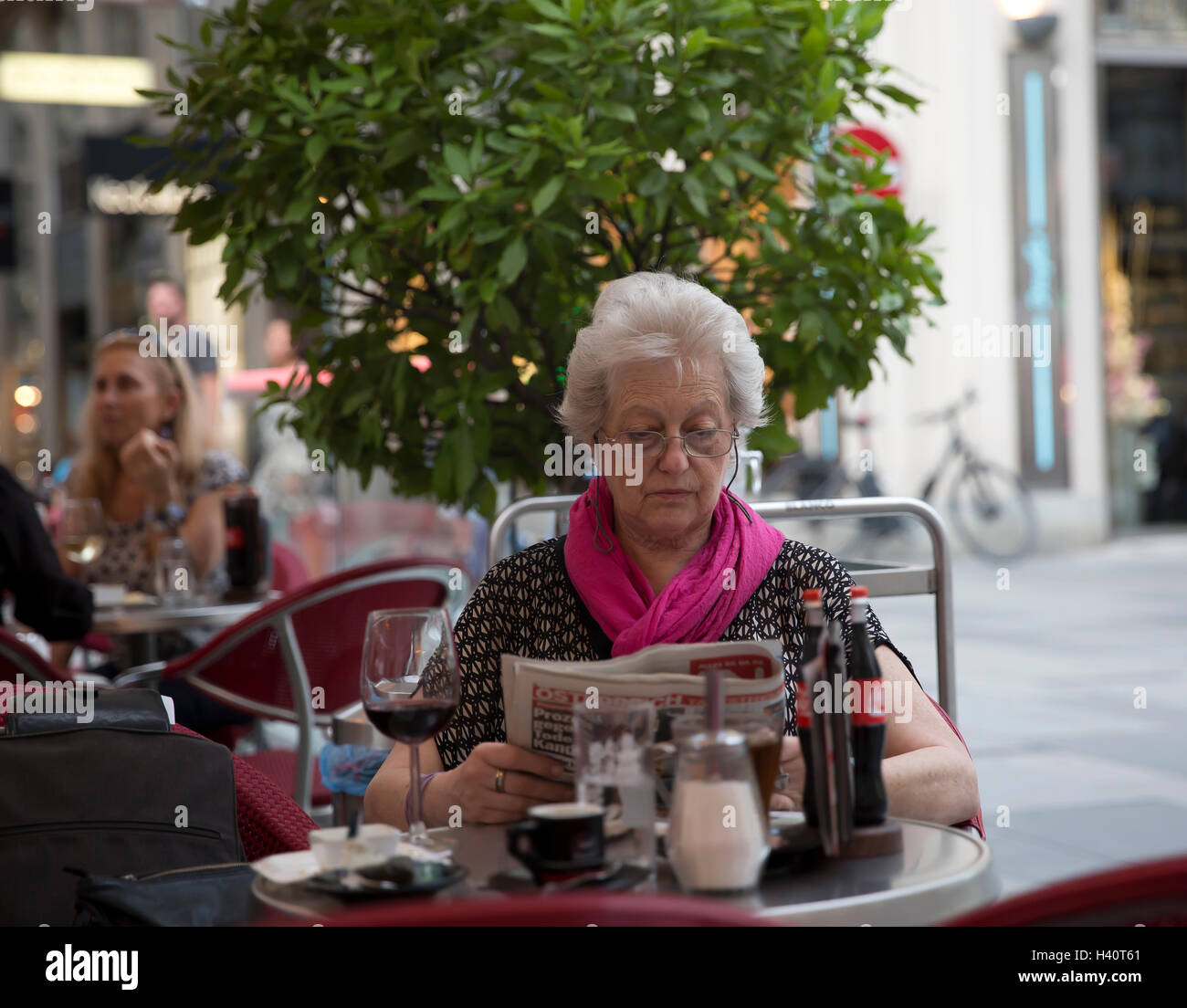 A lady reads a newspaper while dining Al fresco in Vienna Austria Stock ...