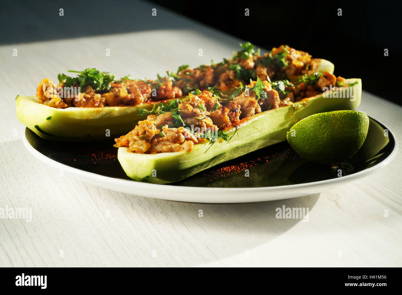 Stuffed zucchini on a black plate decorated with parsley Stock Photo ...