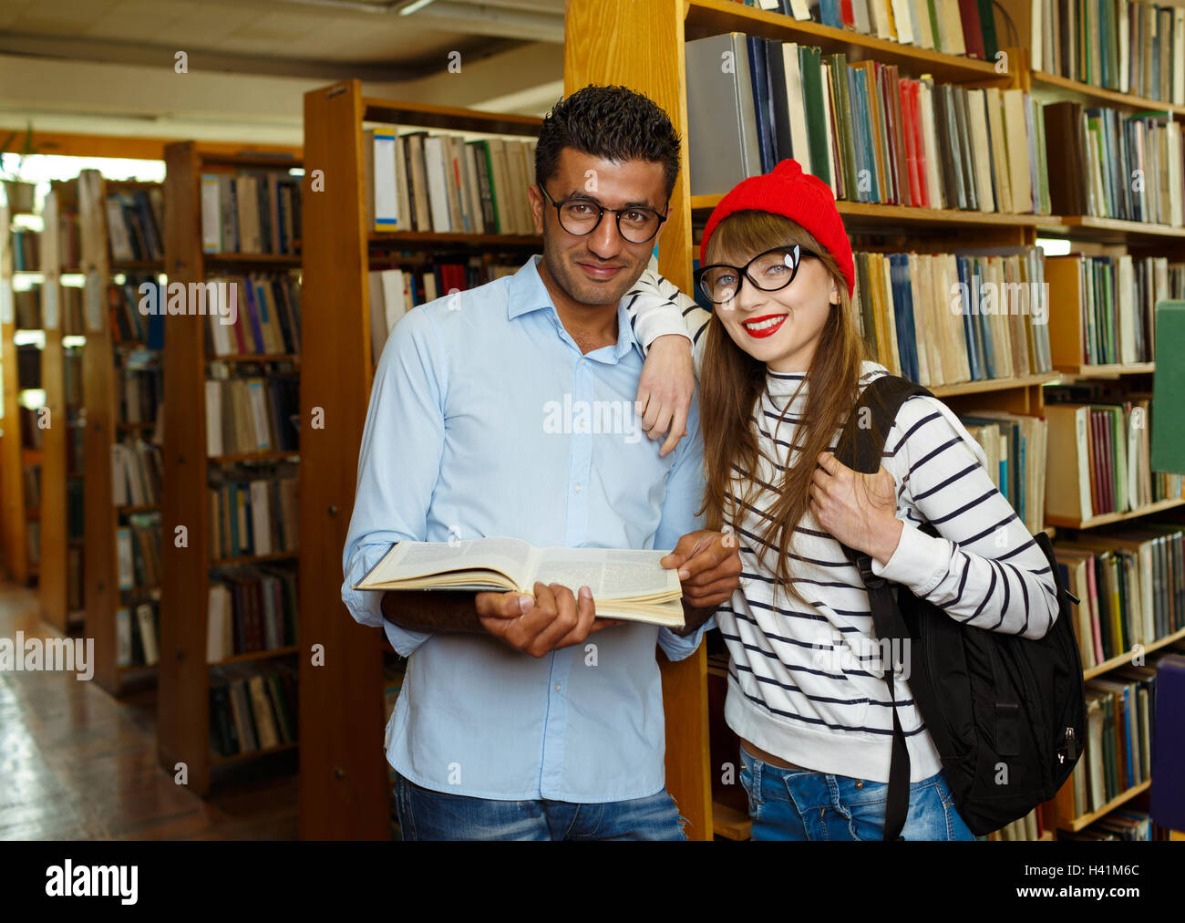 Young student couple choosing books between the shelves in the library ...