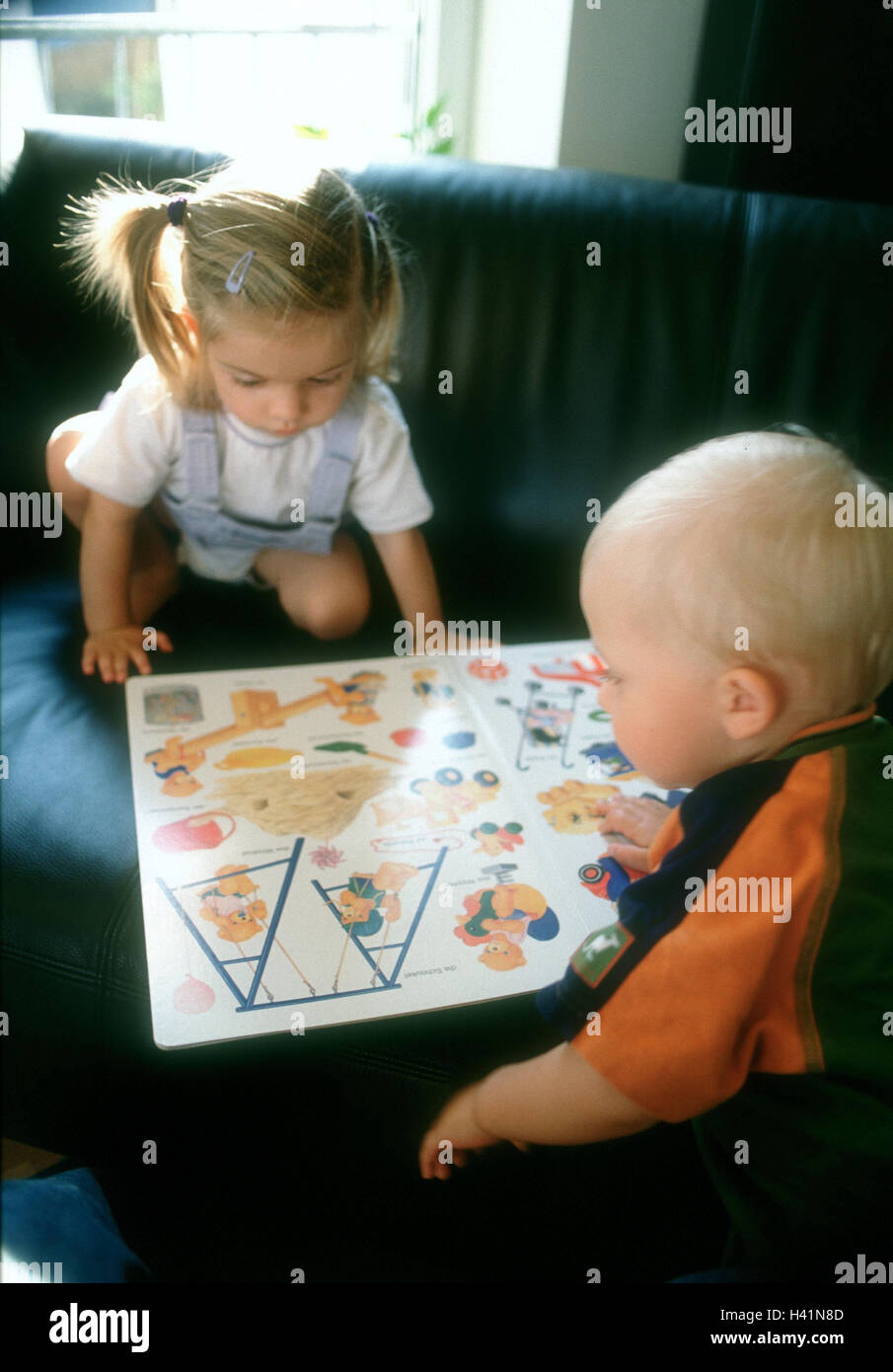 Sofa, children, boy, girl, picture book inside, at home, sitting room ...