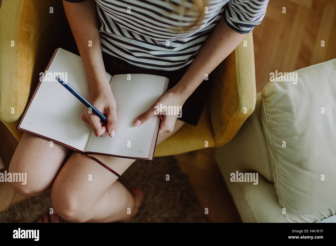 Woman sitting in armchair writing in a notebook Stock Photo - Alamy