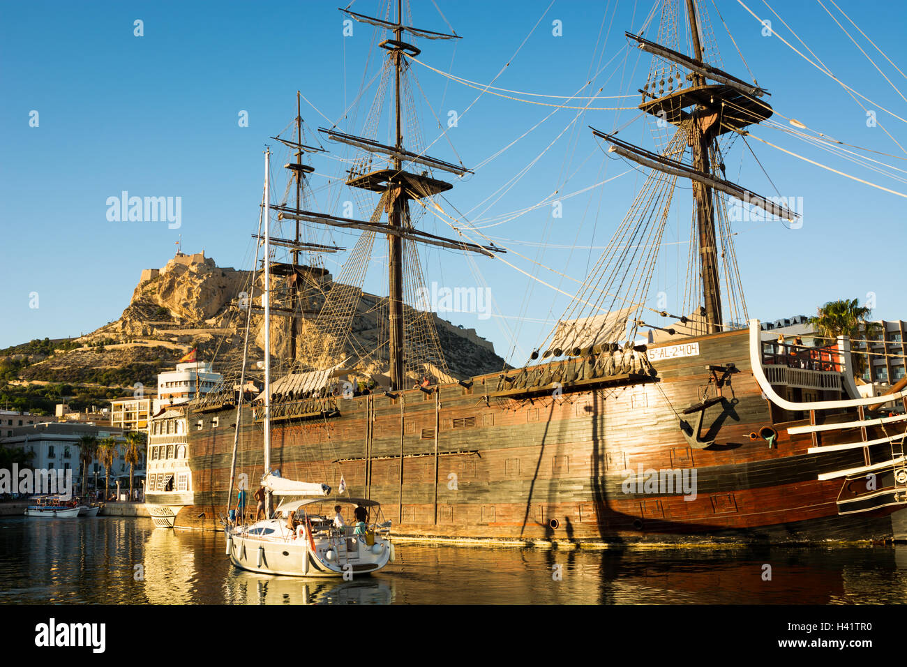 A modern small sailboat passes in front of an ancient war galleon Stock ...