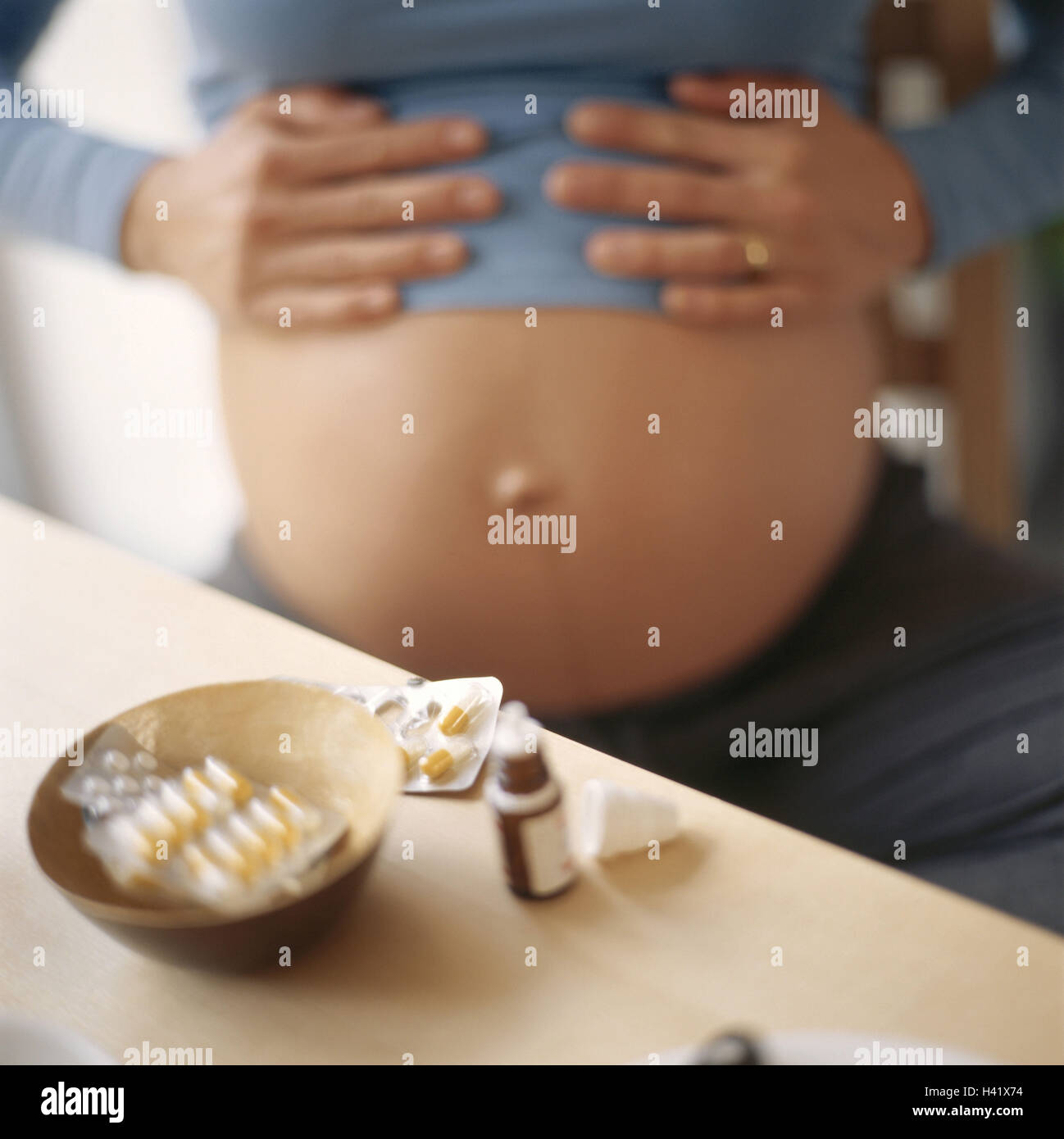 Woman, pregnant, sit, hands, touch, abdomen, table, drugs, capsules ...