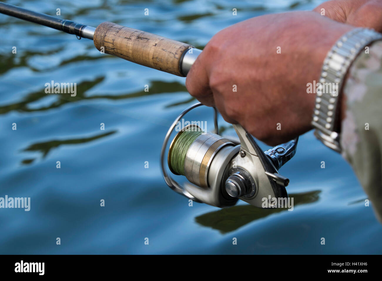 Hands of Mari man holding fishing rod in river Stock Photo - Alamy