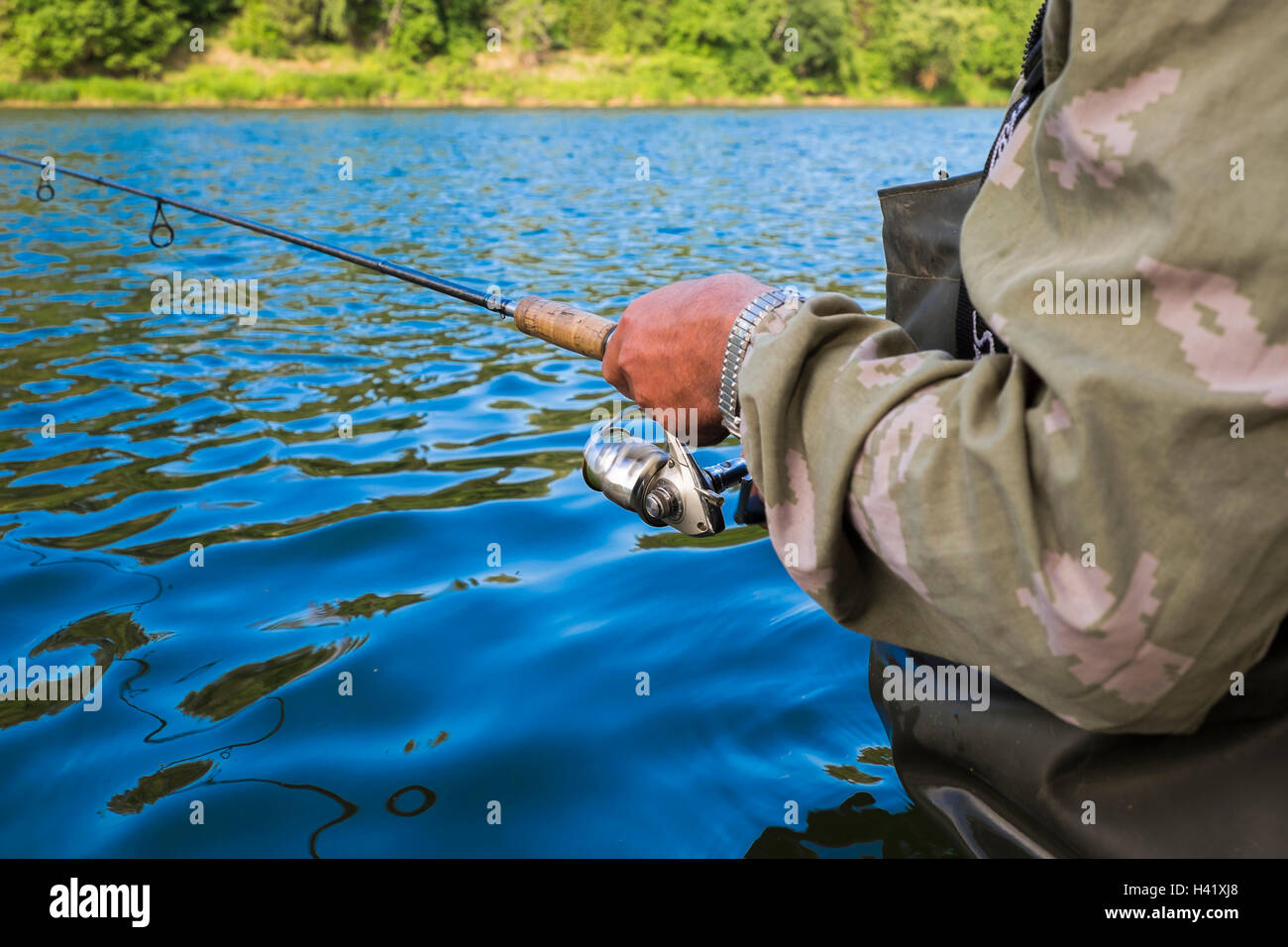 Mari man holding fishing rod in river Stock Photo - Alamy