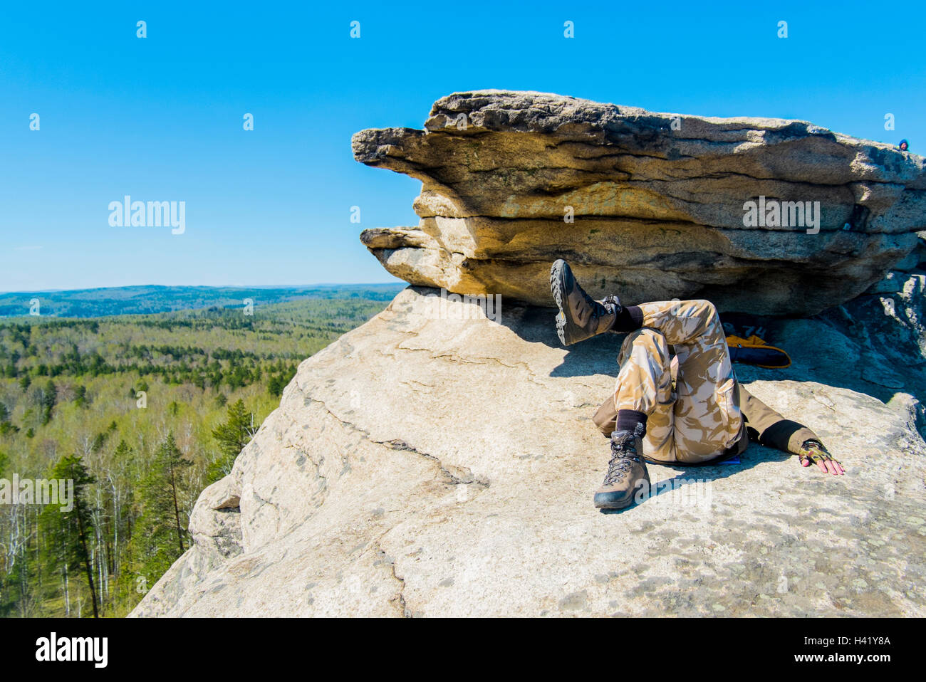 Caucasian man laying on mountain rock under blue sky Stock Photo - Alamy